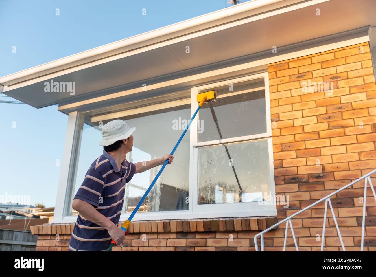 Man washing windows with long pole and brush. Home maintenance project ...