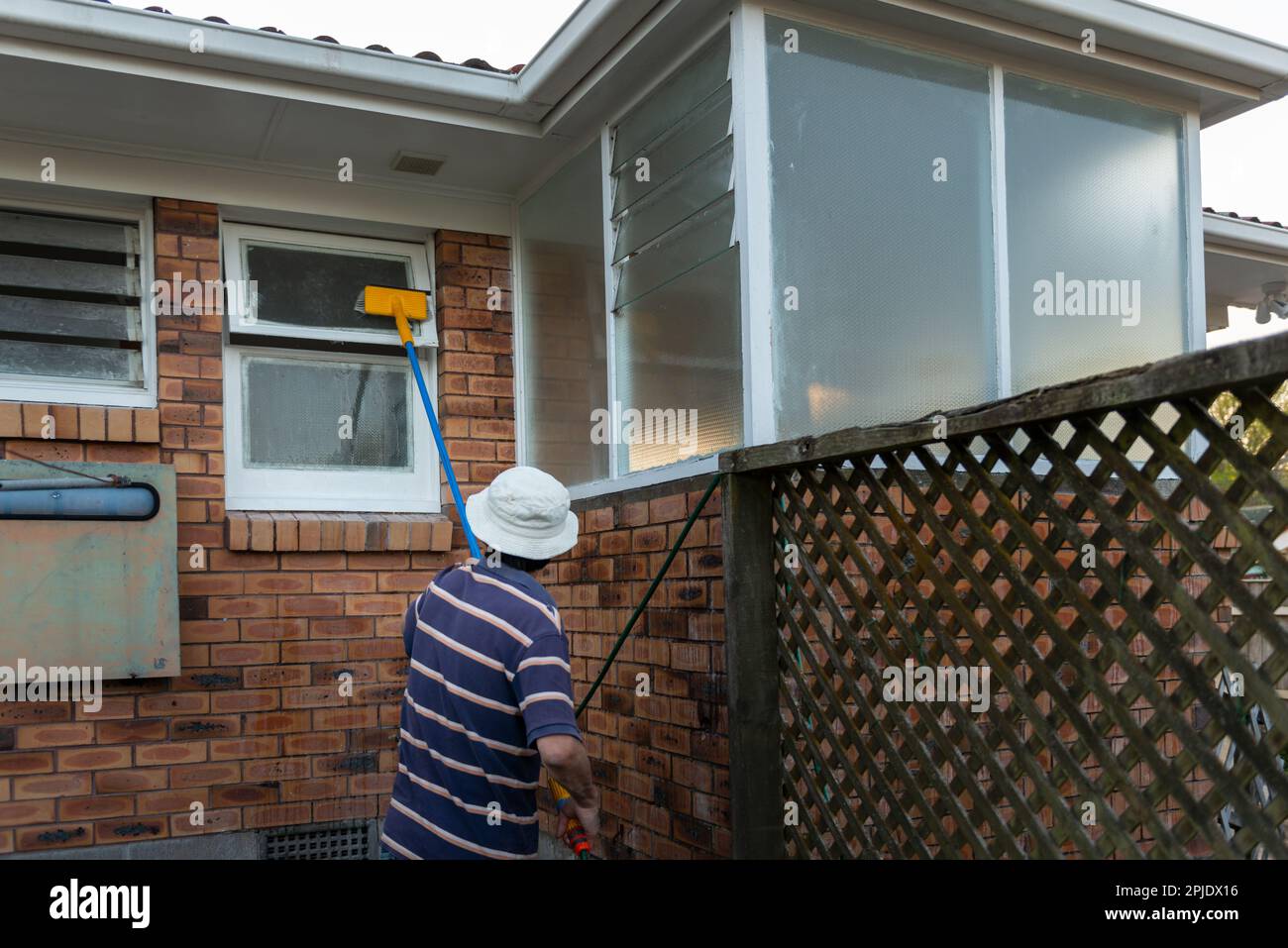 Man washing outside window with long pole and brush. Auckland Stock ...