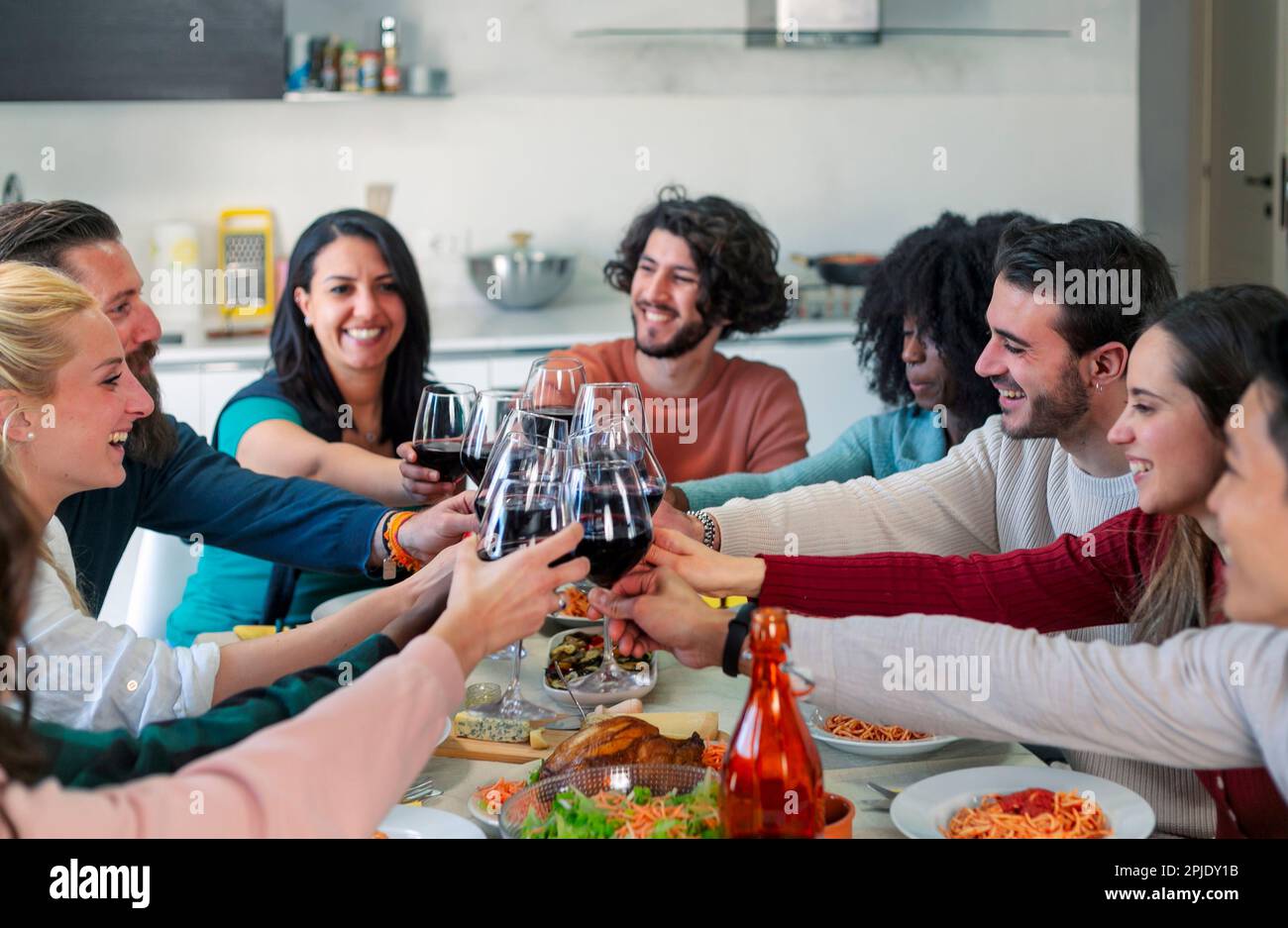 young people holding wine glasses and toasting while celebrating ...