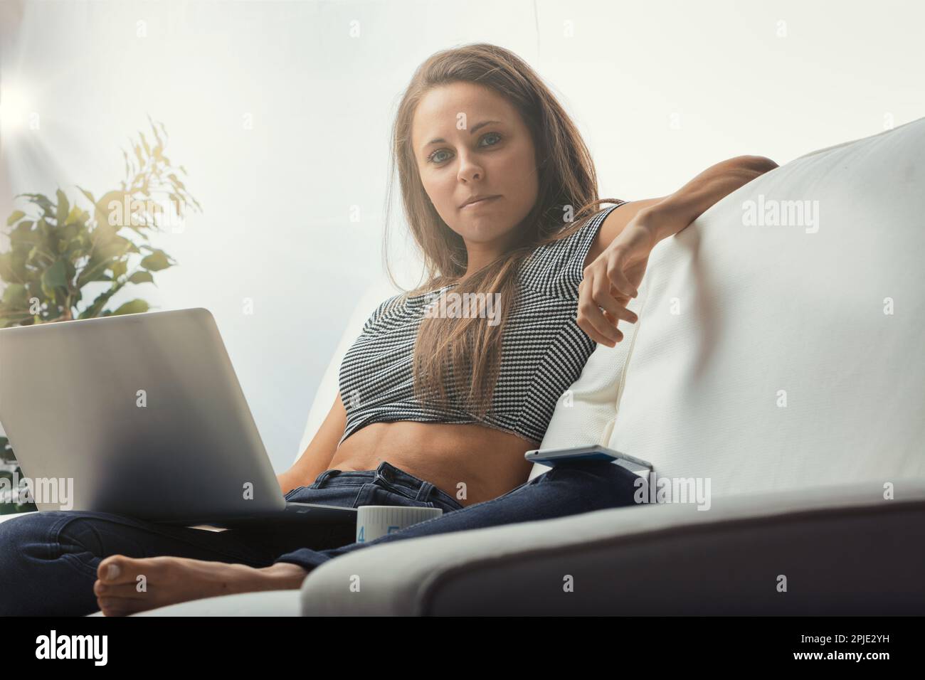 A Barefoot Girl Sits On The Couch Relaxed Yet Engaged With Something 2221