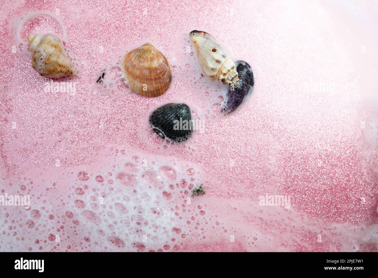 White foam, water and pink glitter with sea shells, abstract sea shore backdrop, soft focus ...