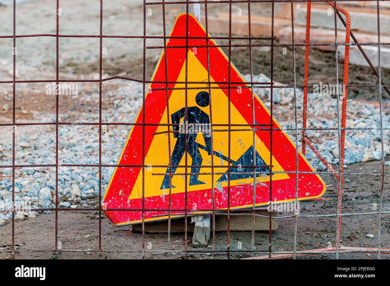 Men at work sign behind the steel wire fence on construction site ...