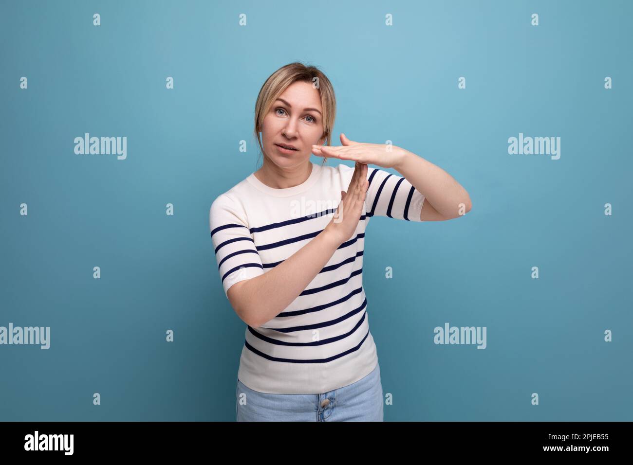 blond girl shows hand gesture letter t on blue background with copy ...