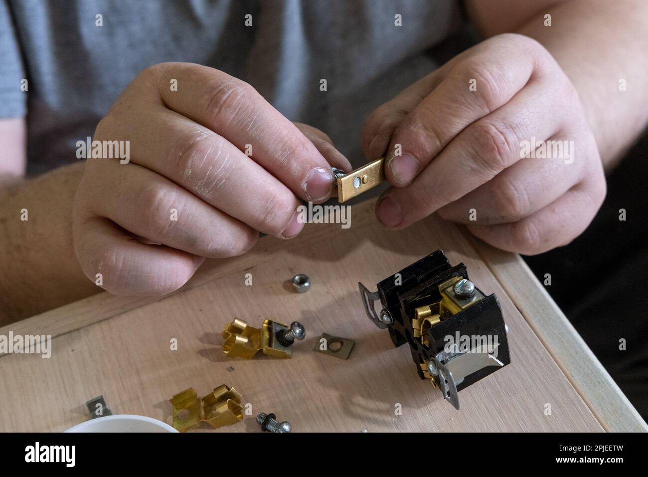 Male hands holding electrical outlet detail close-up. A repairman fixes ...