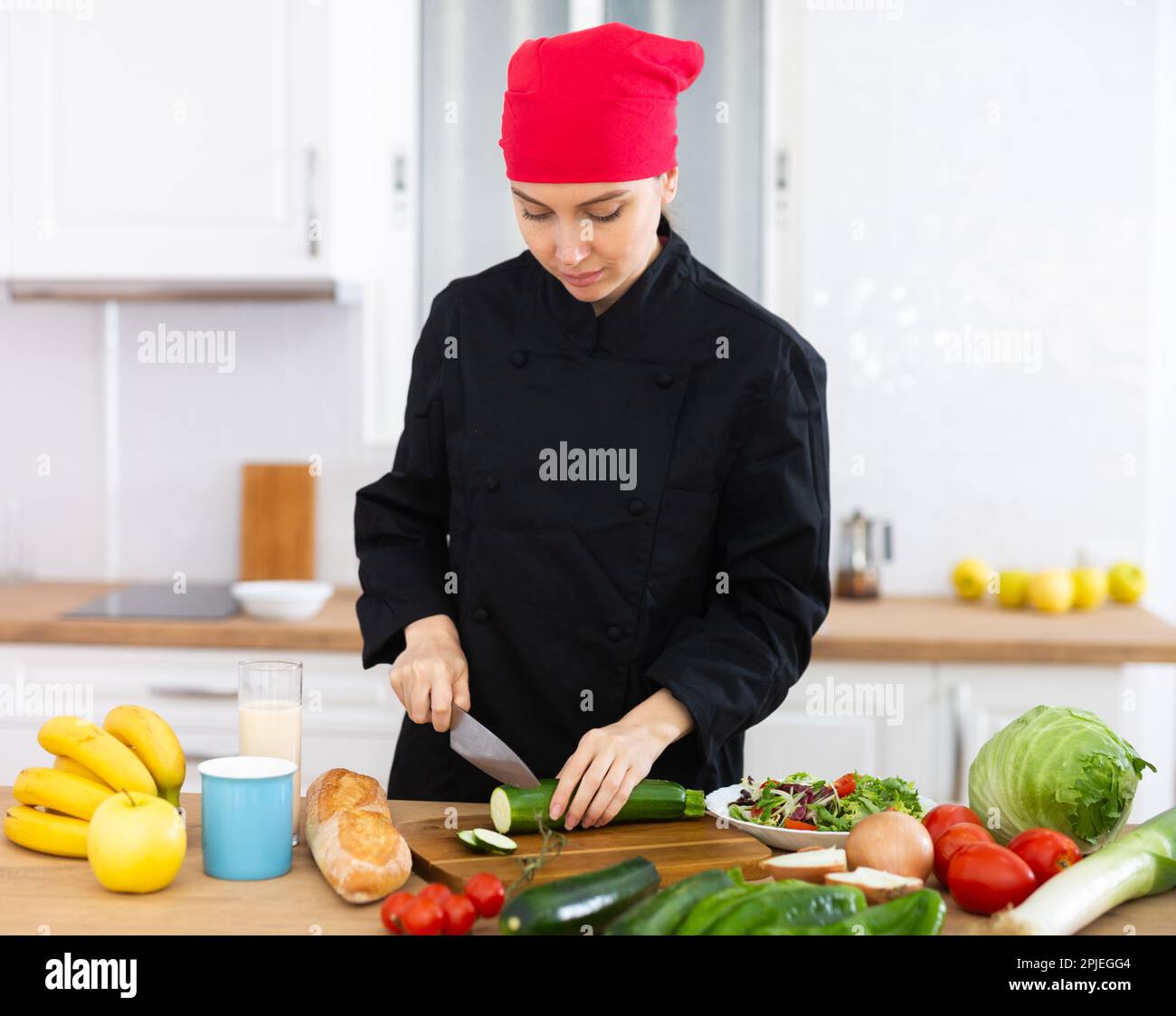 Female cook in black uniform chopping vegetables in kitchen Stock Photo ...