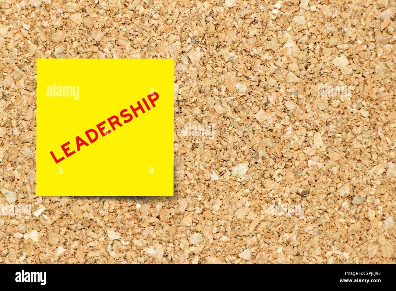 Yellow note paper with word leadership on cork board background with ...