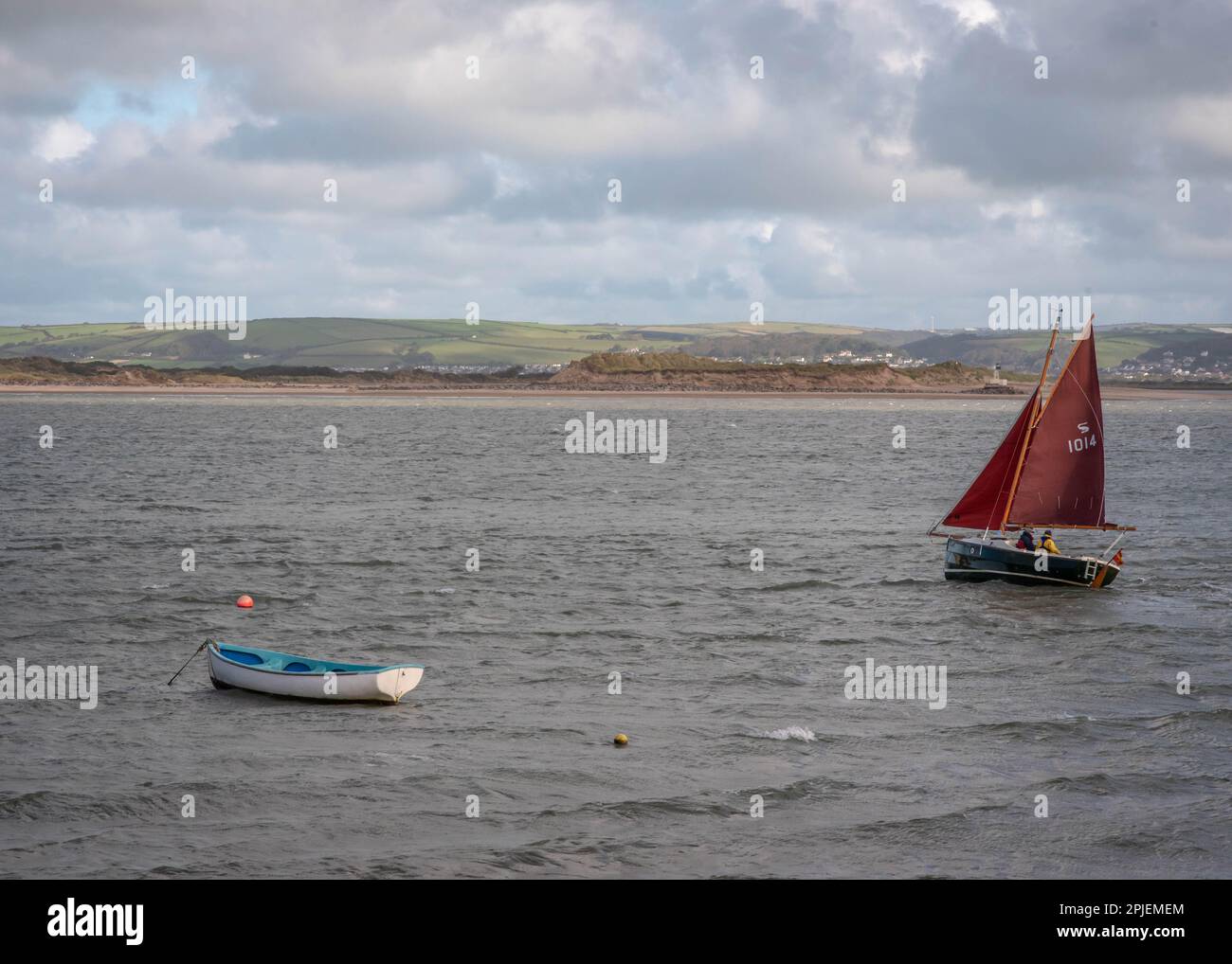 Sailing boat with red sails alongside a blue and white rowing boat ...