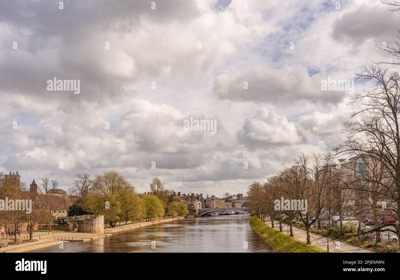 A river flows towards a historic iron bridge with a cloud filled sky ...