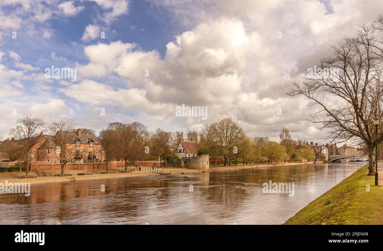 A river flows towards a historic iron bridge with a cloud filled sky ...