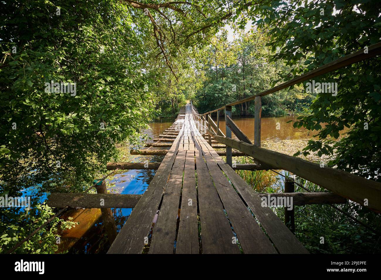 Wooden suspension bridge. Pedestrian hanging bridge over Naroch river ...