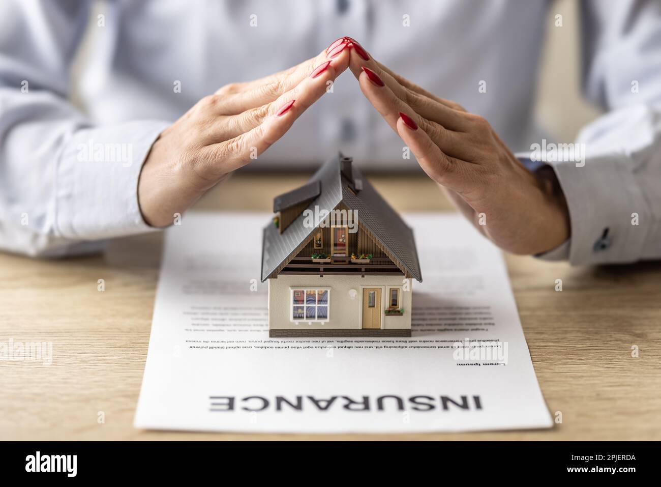 Female hands expressing extra protection over the house model on top of ...