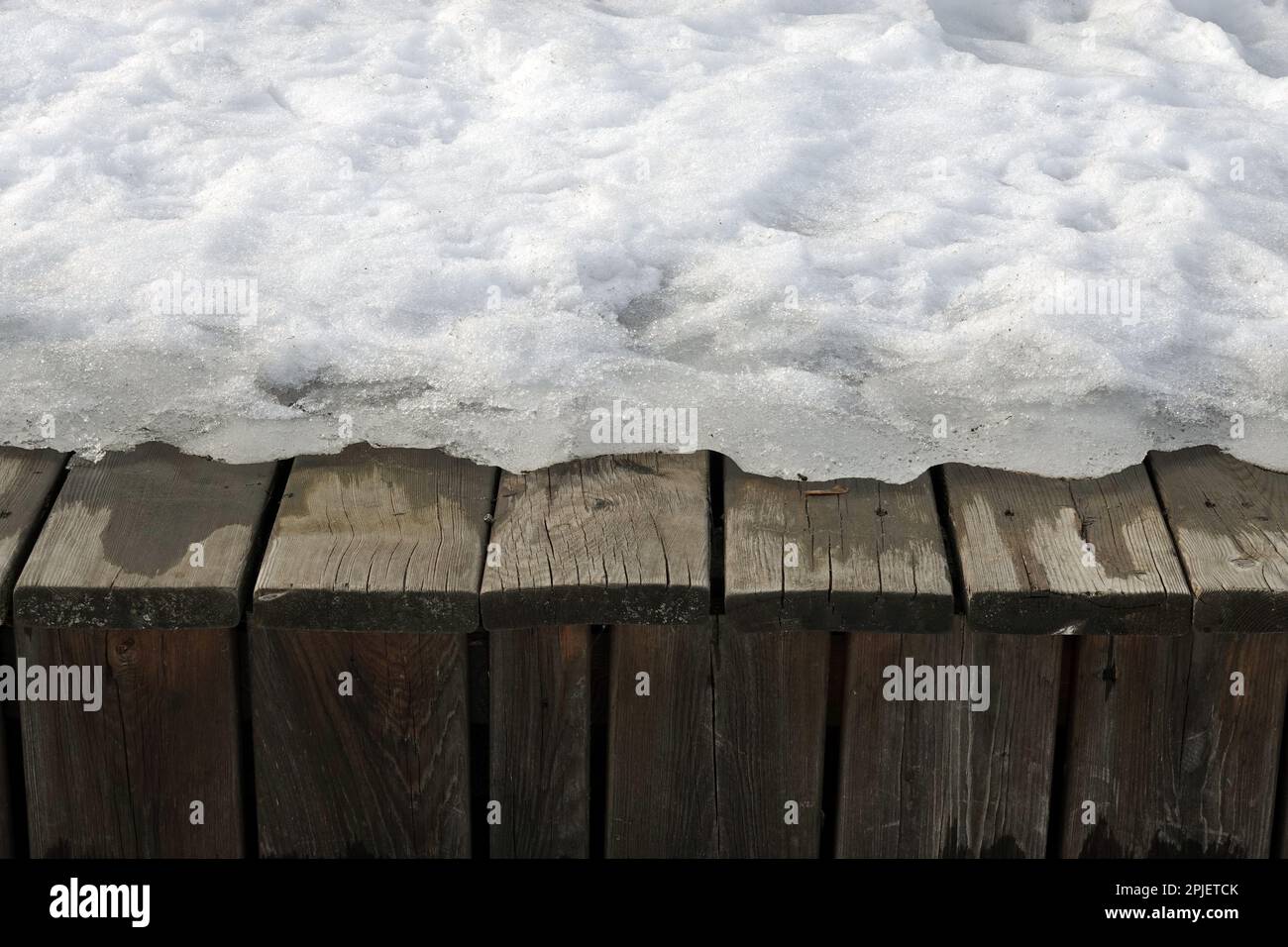 Melting on spring snow on the old brown wooden boards surface outdoors ...