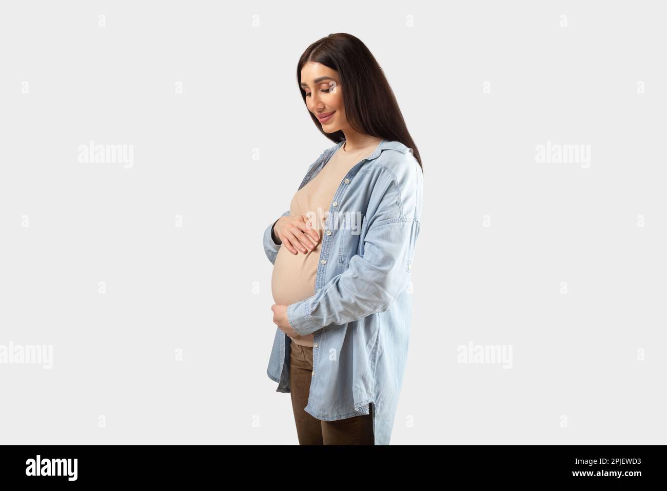 Positive young pregnant lady embracing belly and smiling, Beautiful ...