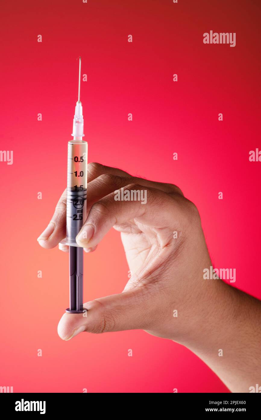 Female hand holding injection on red background Stock Photo - Alamy