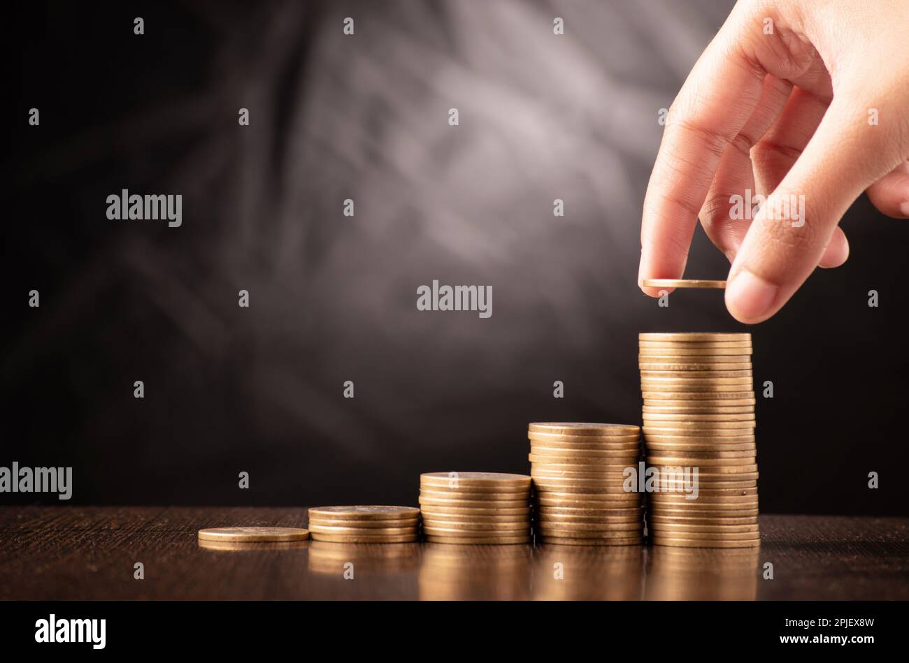 Putting coin in stack investing in business Stock Photo - Alamy