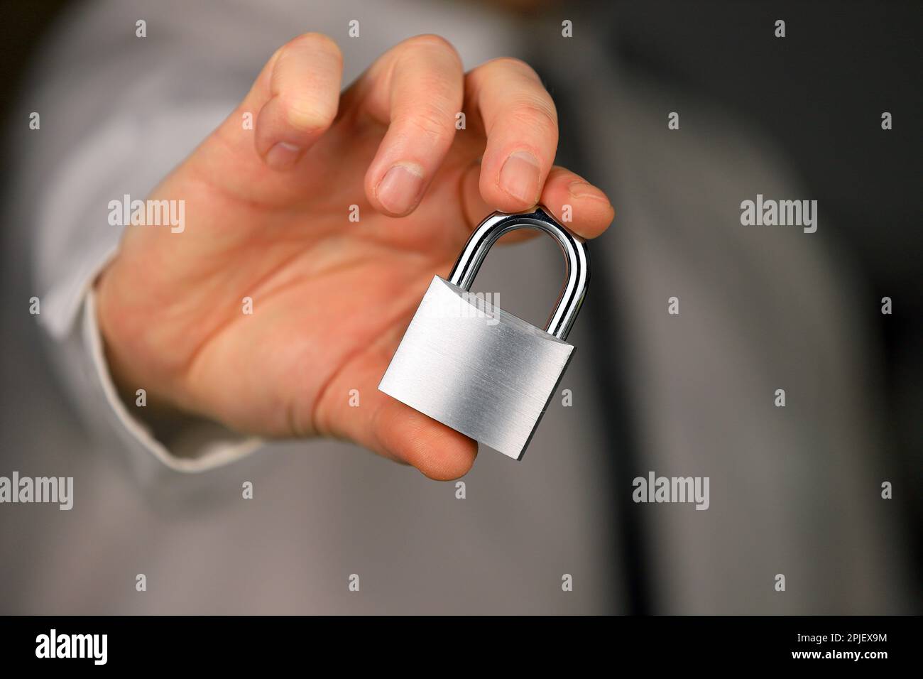 A businessman in a white shirt and black tie holds a silver padlock in ...