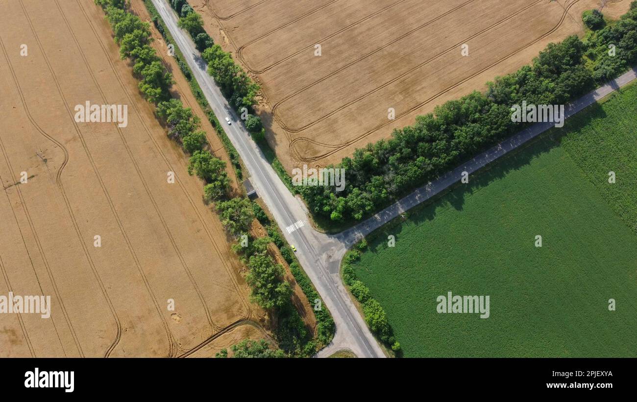 Automobile asphalt road with cars driving along it between agricultural ...