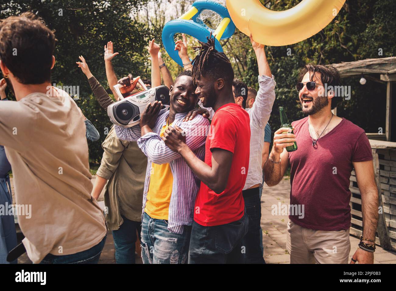 At an outdoor summer party in a cool grove, people dance and enjoy beer ...