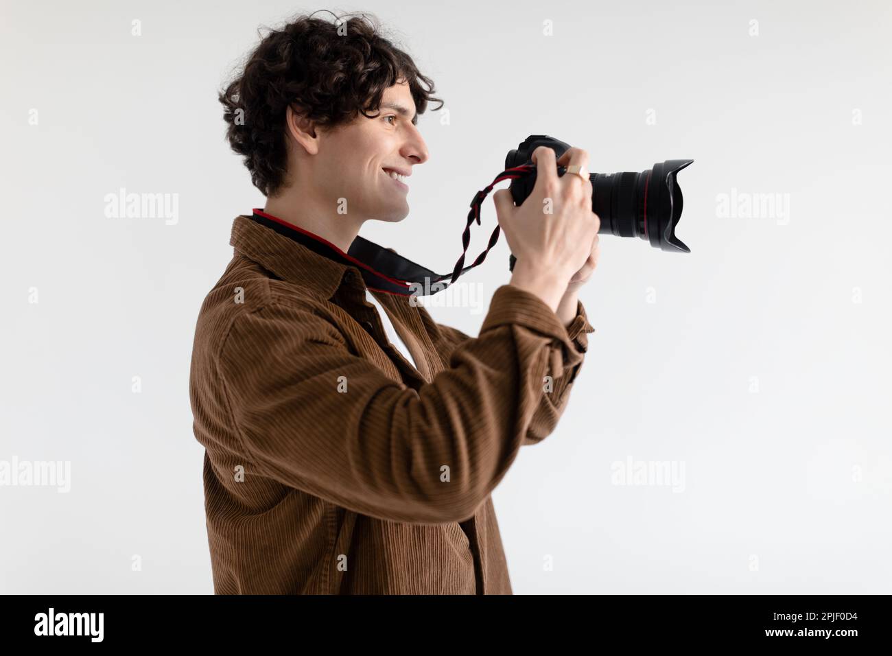 Positive male photographer taking photo holding camera near face and ...