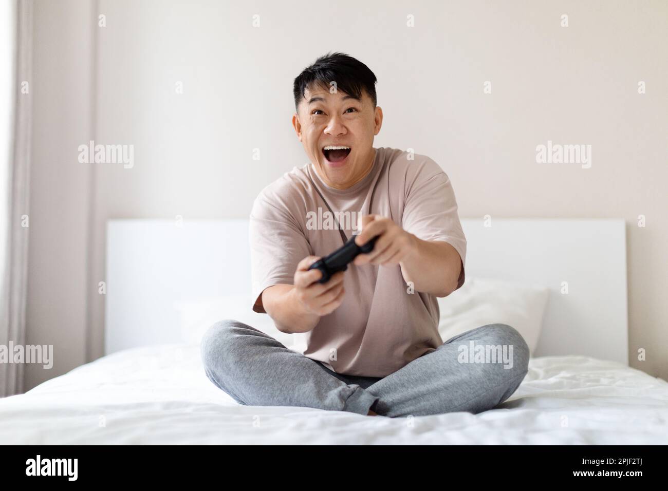 Happy emotional adult chinese man playing video games at home Stock ...