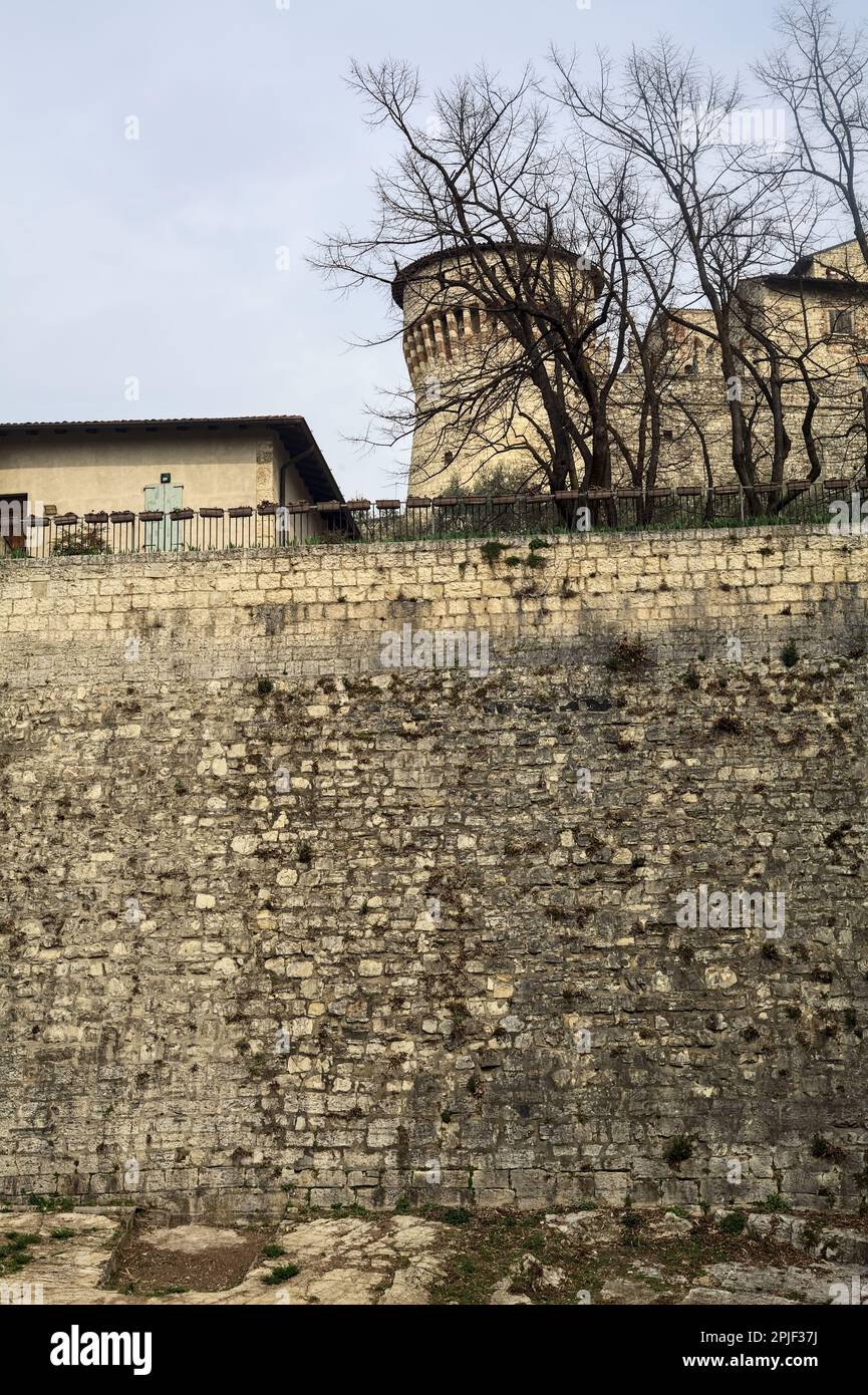 Outer boundary wall of a castle with trees and a cloudy sky as ...