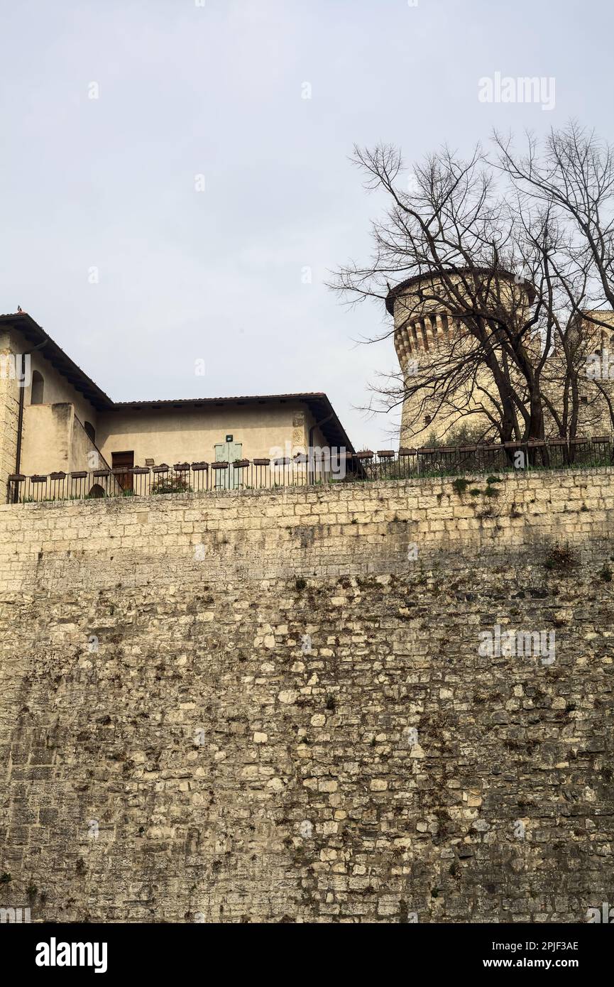 Outer boundary wall of a castle with trees and a cloudy sky as ...