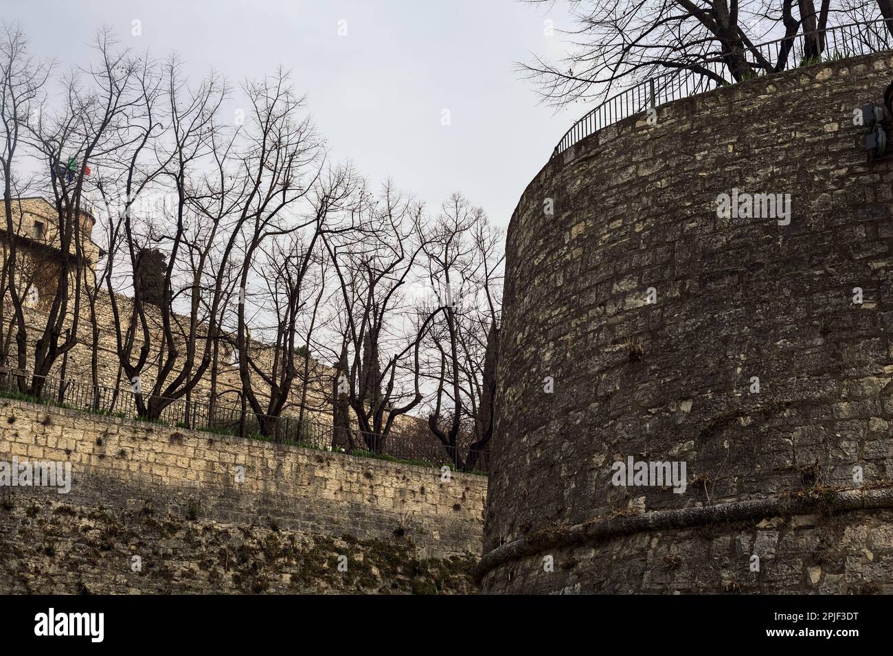 Outer boundary wall of a castle with trees and a cloudy sky as ...
