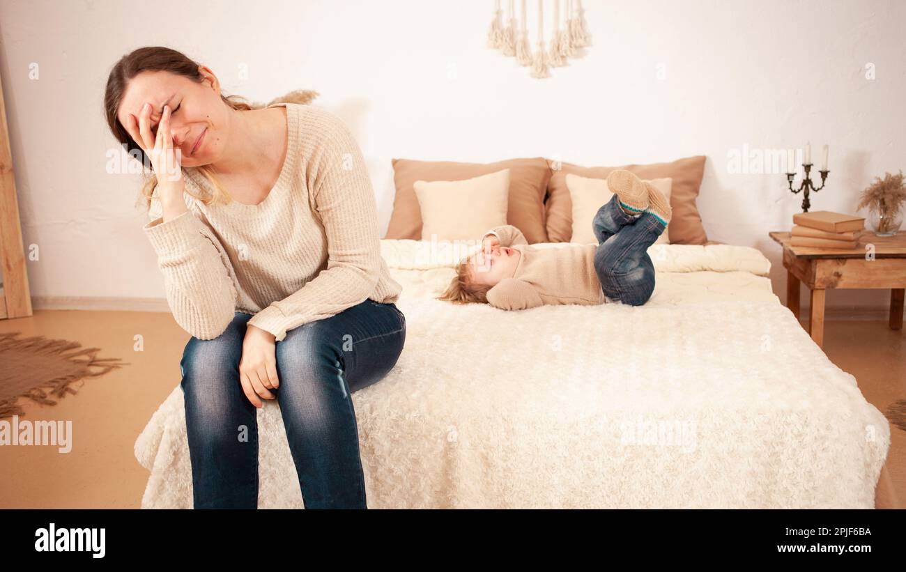 Mom's tired of the baby. A two-year-old girl lying on the bed ...