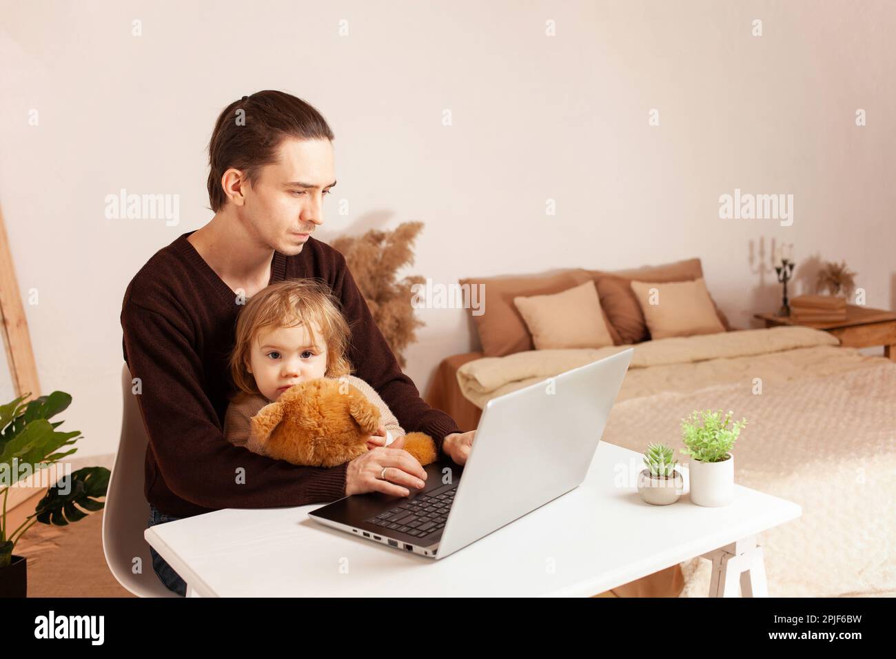 A man works at home on a laptop. The child distracts from work, misses ...