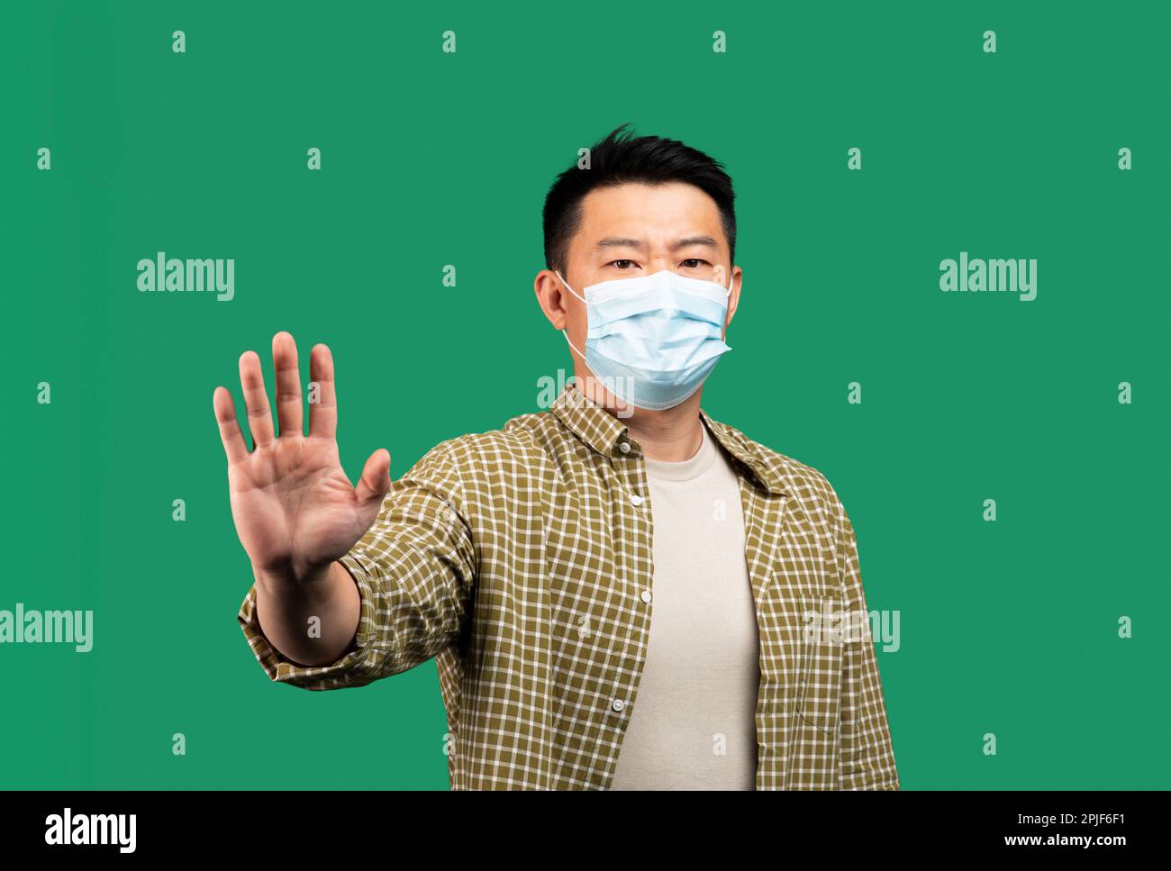 Displeased korean middle aged man with protective mask showing stop ...