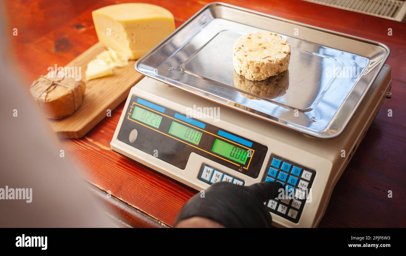 The cheesemaker weighs cheese on scales, home production, business ...