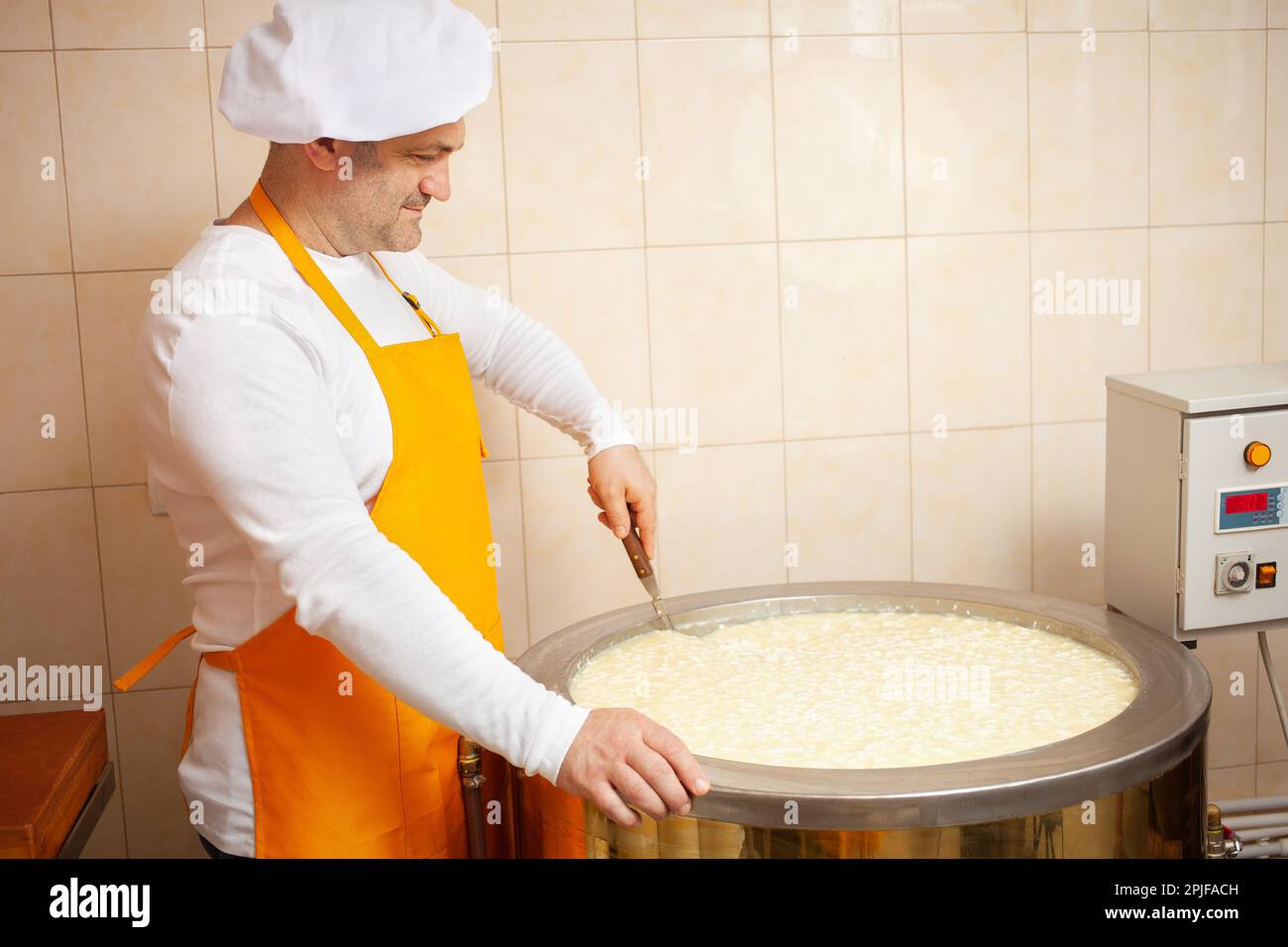man makes cheese, boils milk in cistern, heating, temperature. Milk ...