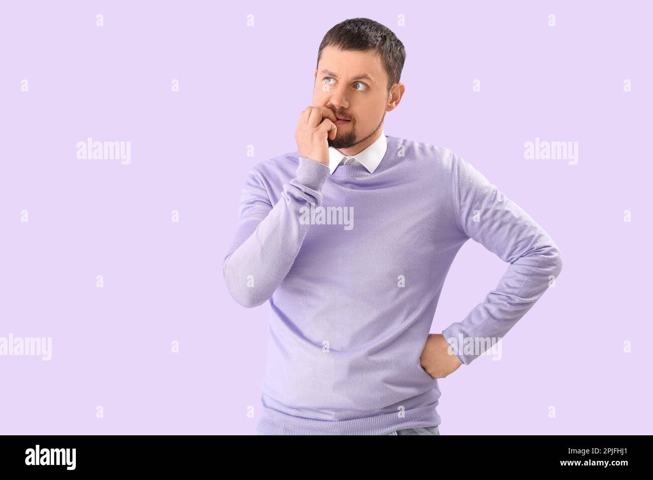 Handsome man biting nails on lilac background Stock Photo - Alamy