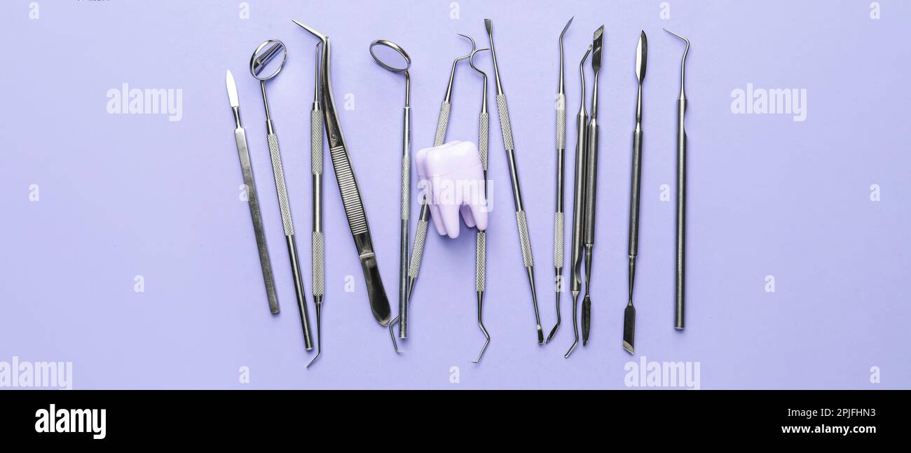 Dentist's tools and model of tooth on lilac background Stock Photo - Alamy