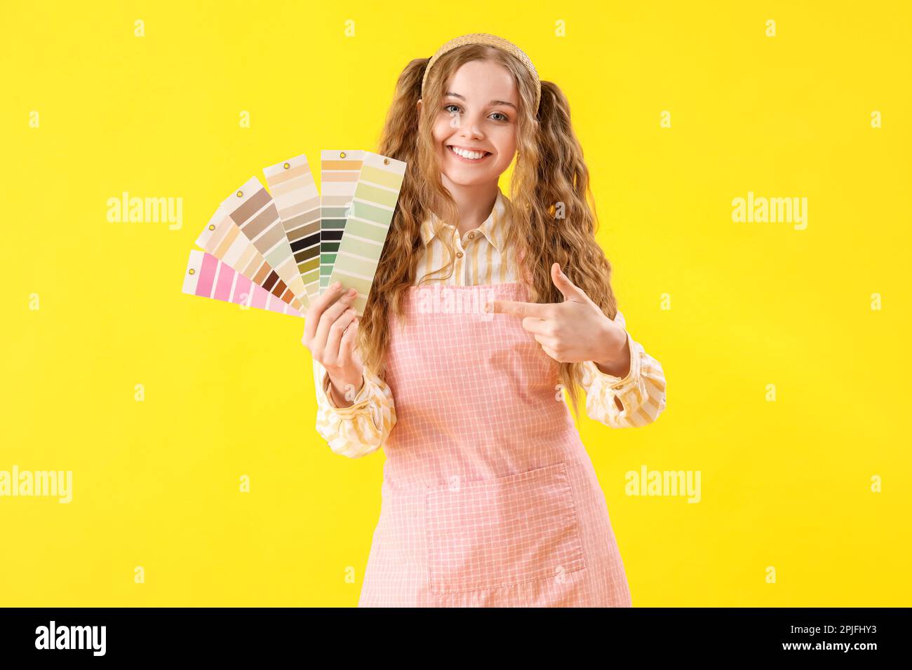Female artist pointing at paint color palettes on yellow background ...
