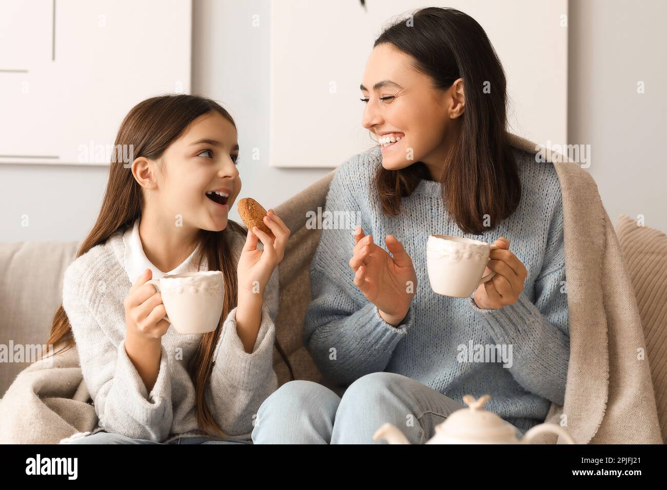 Little girl with her mother drinking tea at home Stock Photo - Alamy