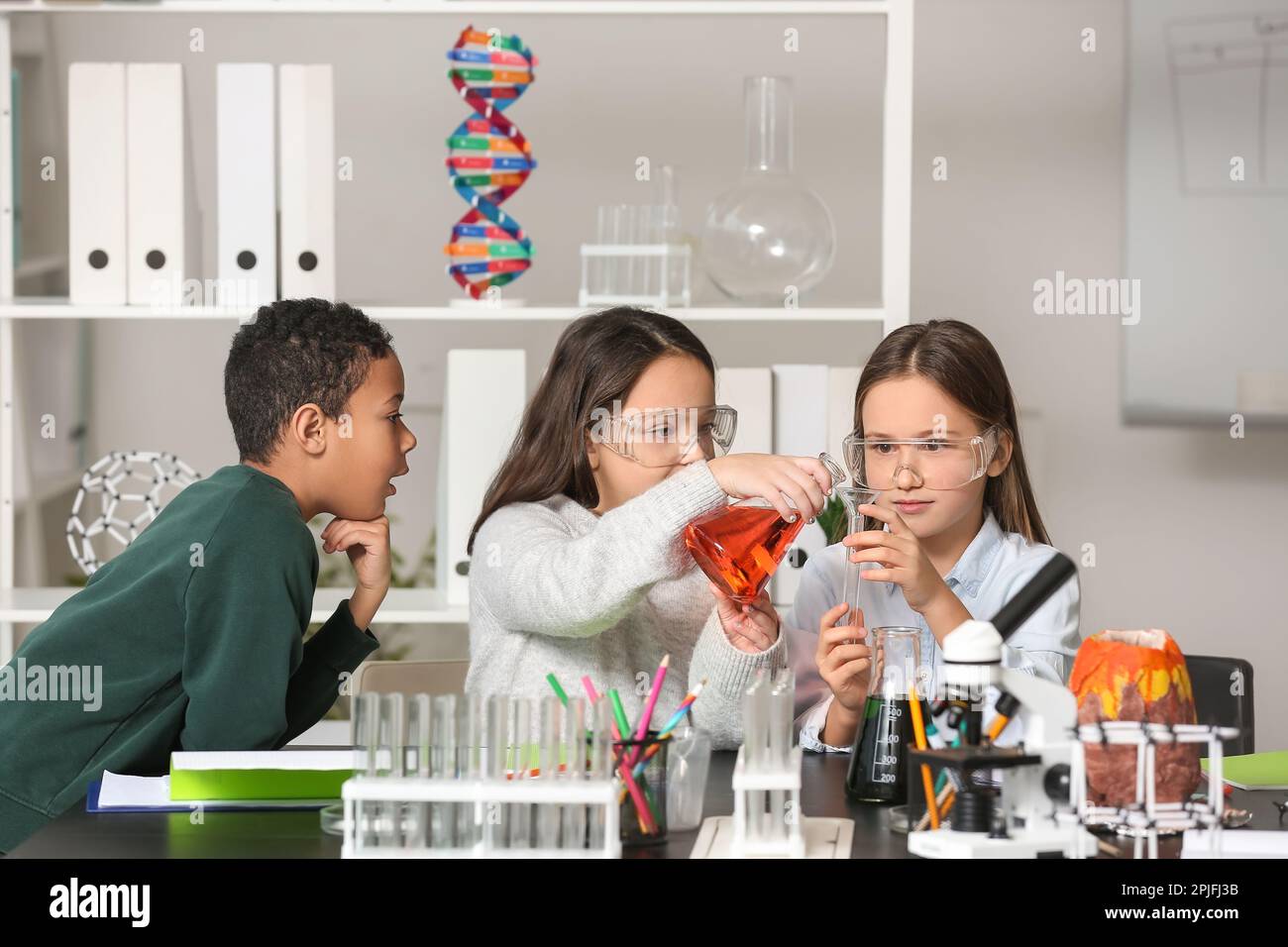 Little children conducting chemistry experiment in science classroom ...