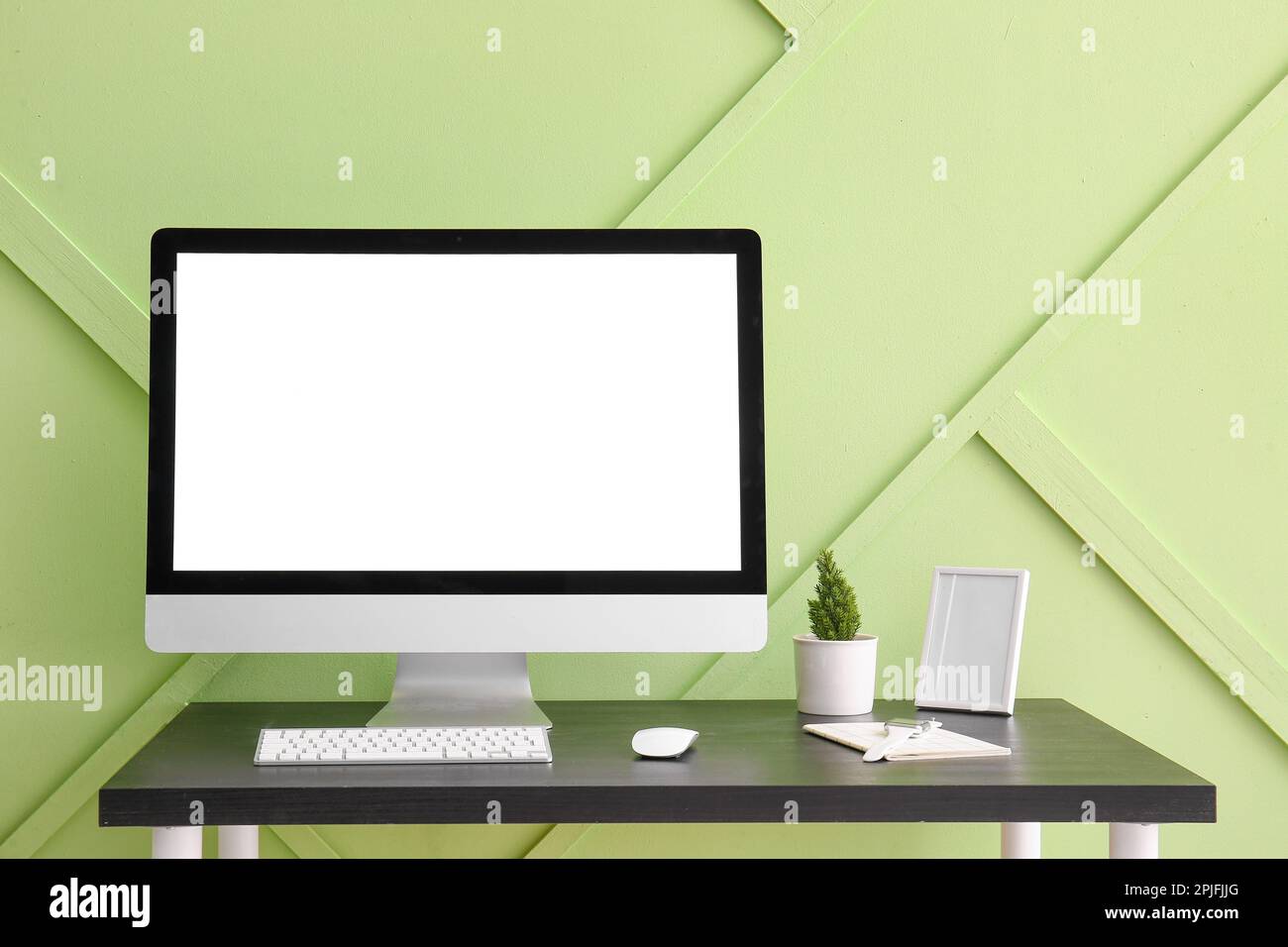 Workplace with computer, smartwatch and frame near green wall Stock ...