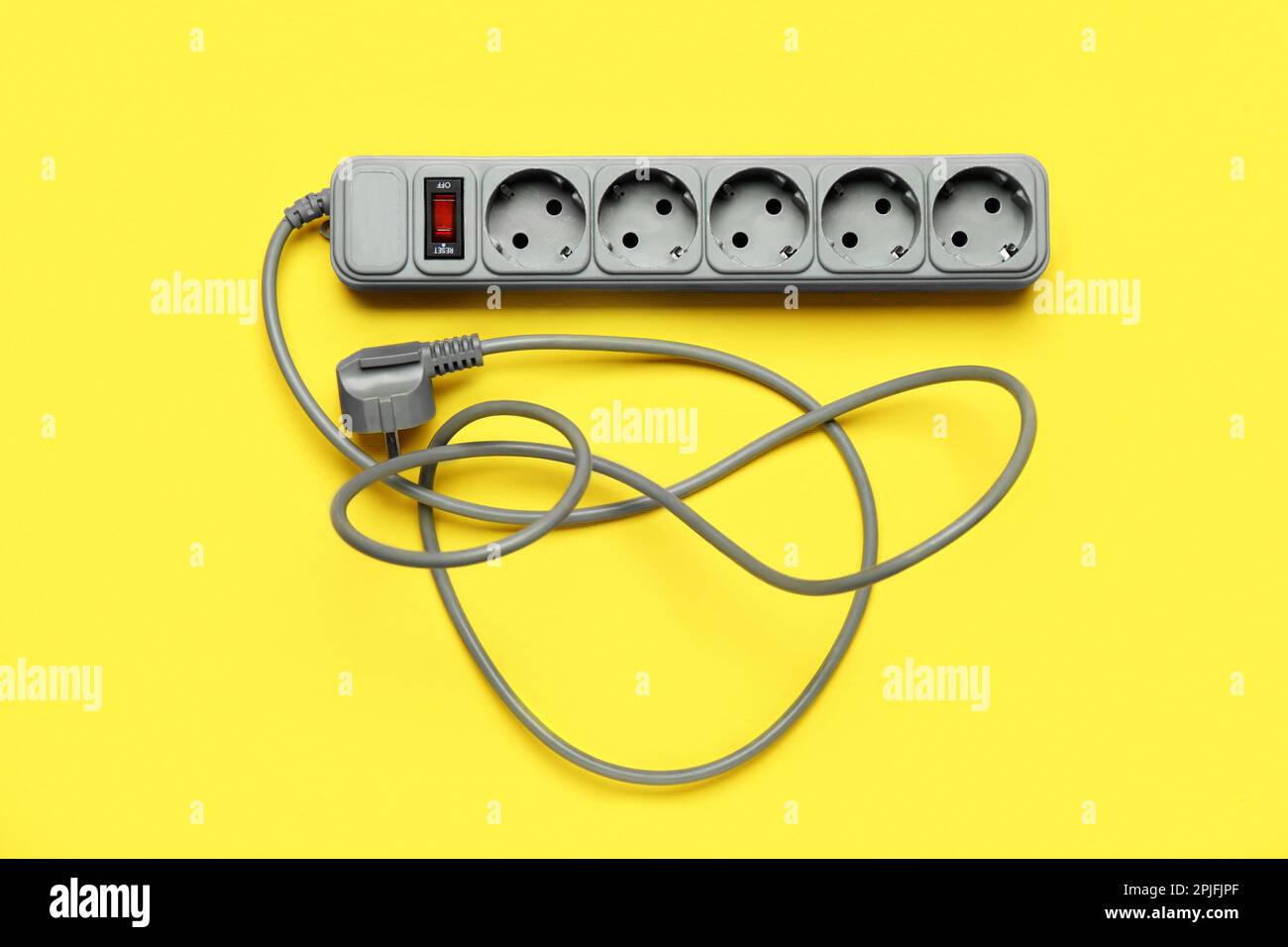 Electric extension cord on yellow background Stock Photo - Alamy