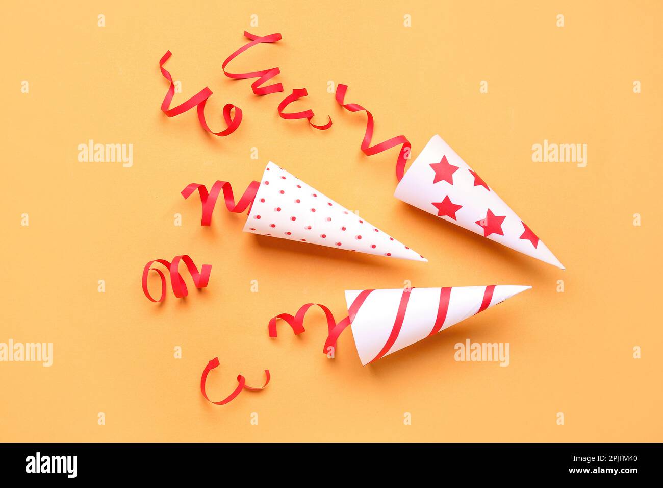 Party cones with serpentine on orange background Stock Photo - Alamy