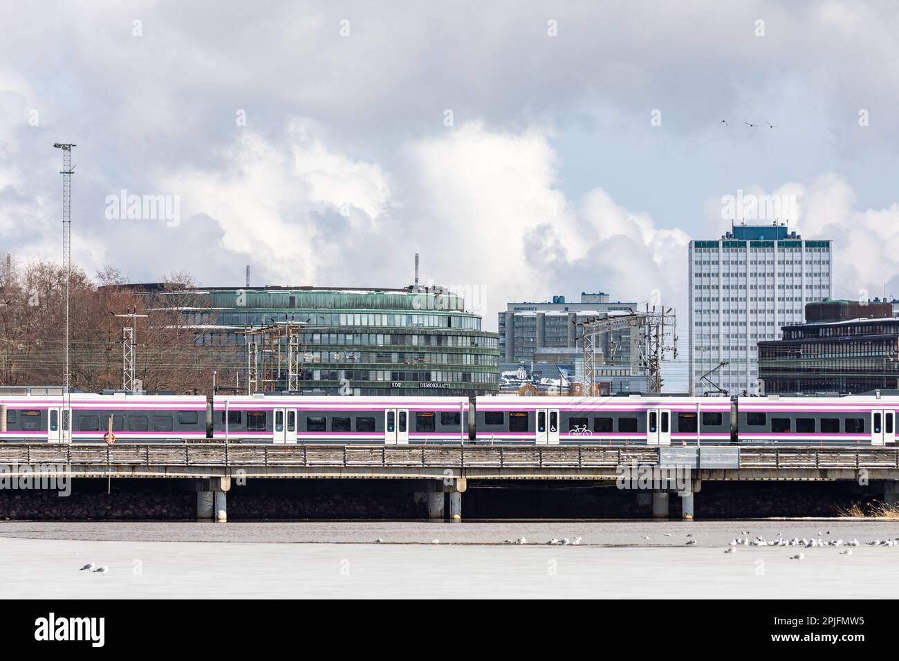 Commuter train passing a railway bridge with Hakaniemi and Merihaka ...