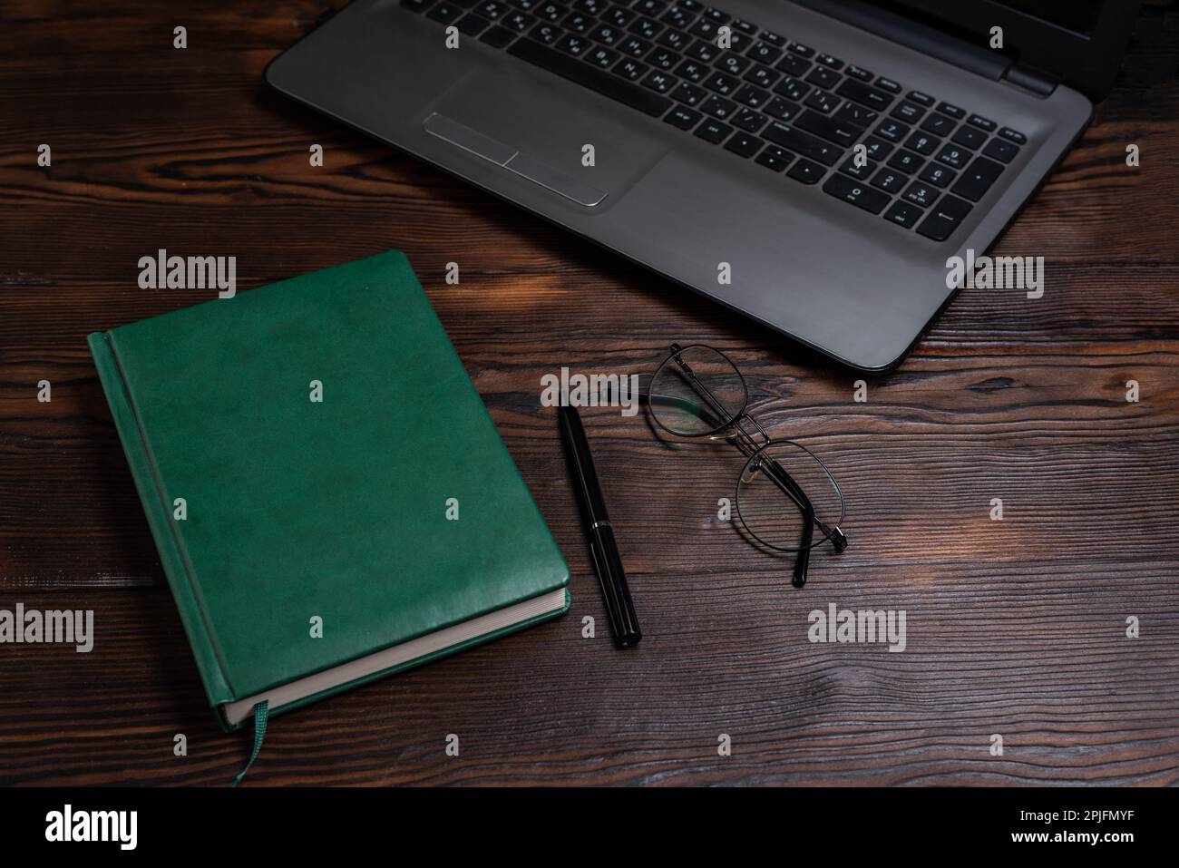 Green diary on the table. Diary and laptop. Notepad, laptop and glasses ...