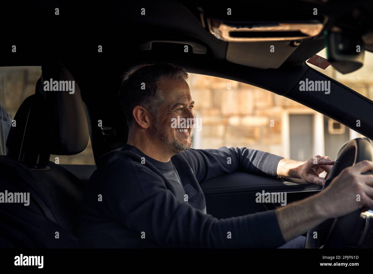 Happy smiling attractive businessman in a casual cloth driving a car in ...