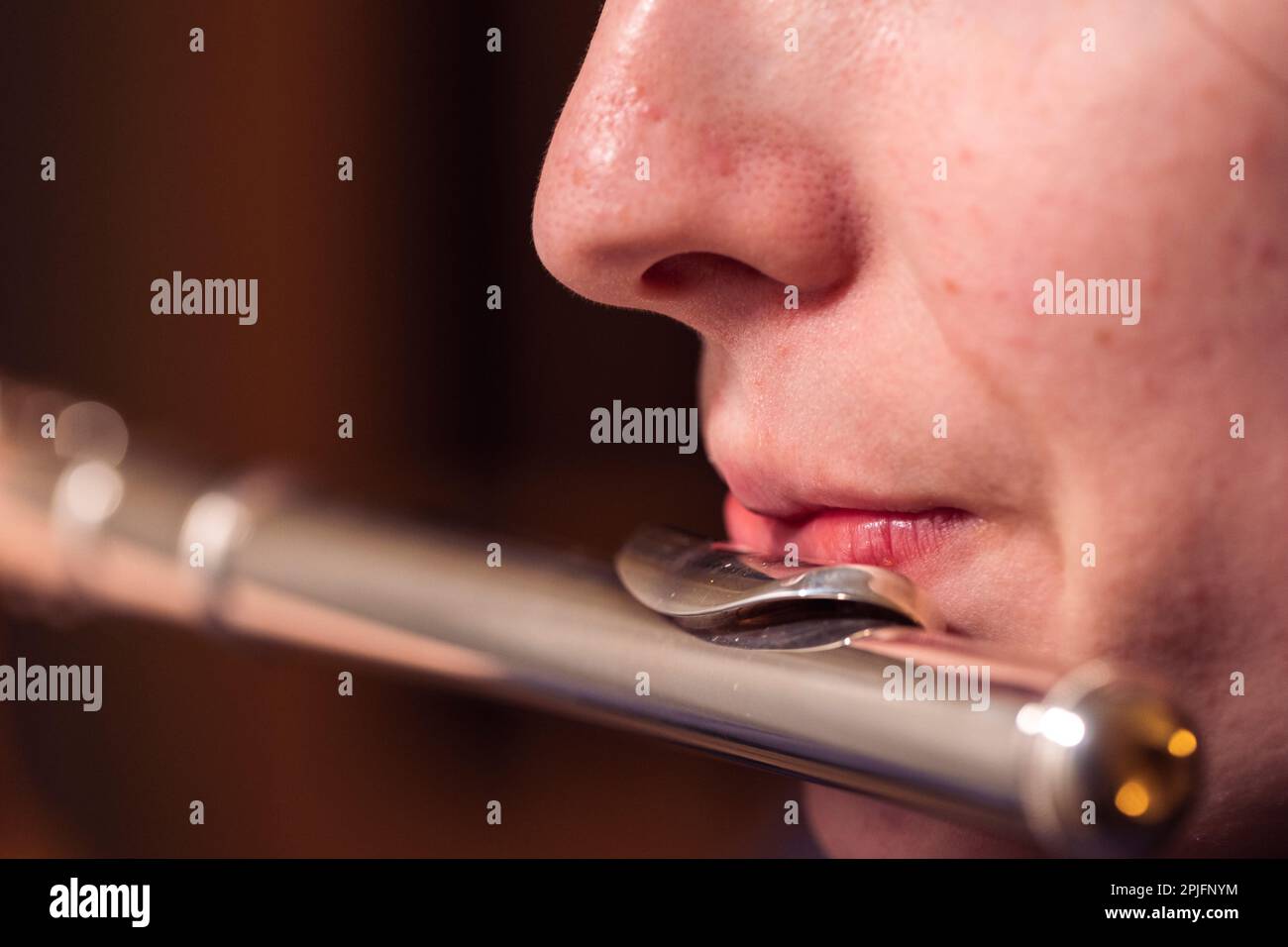 A close up portrait of the mouth of a flutist blowing into the mouth ...