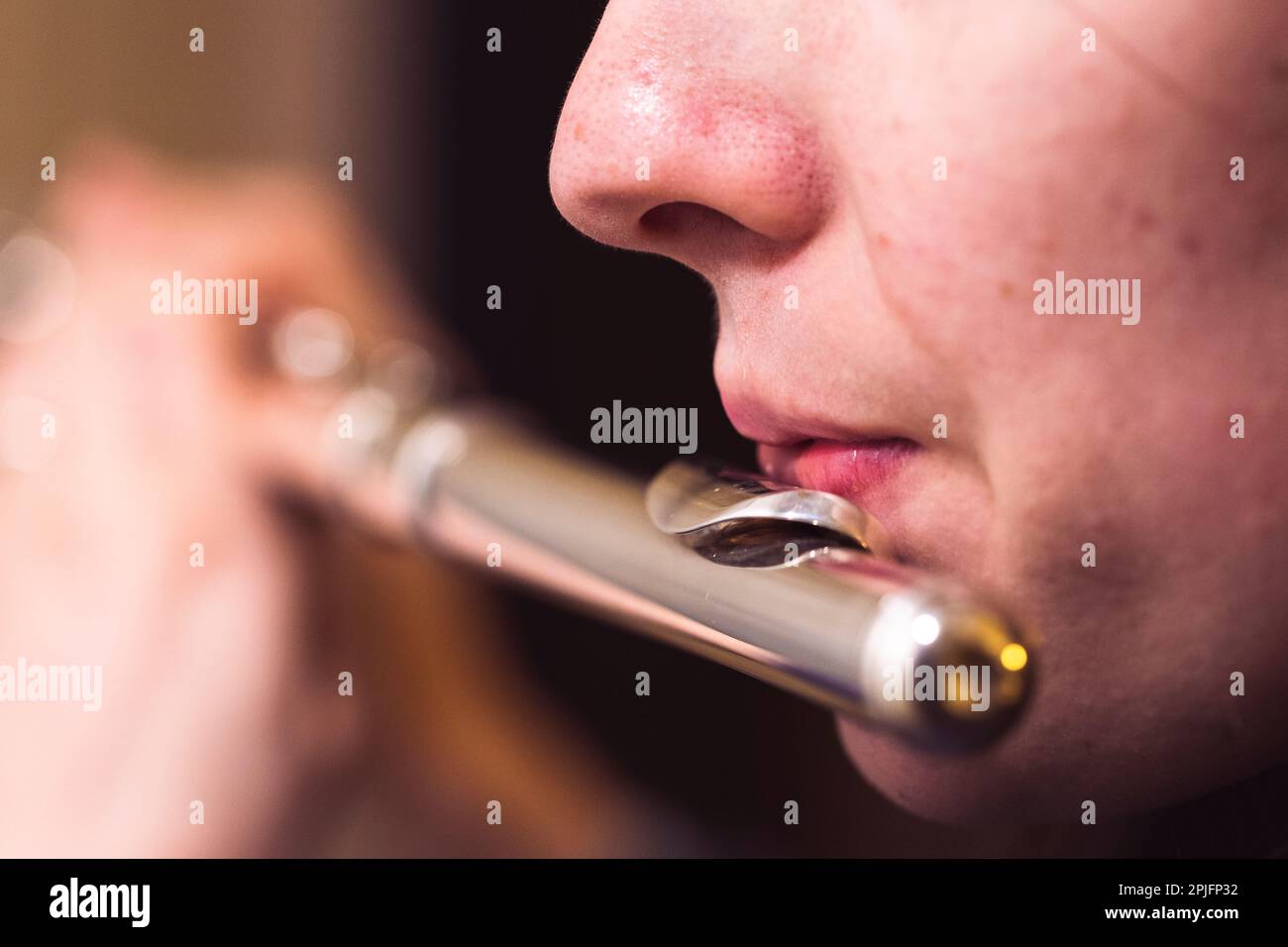 A portrait of the mouth of a flutist blowing into the mouth piece of a ...