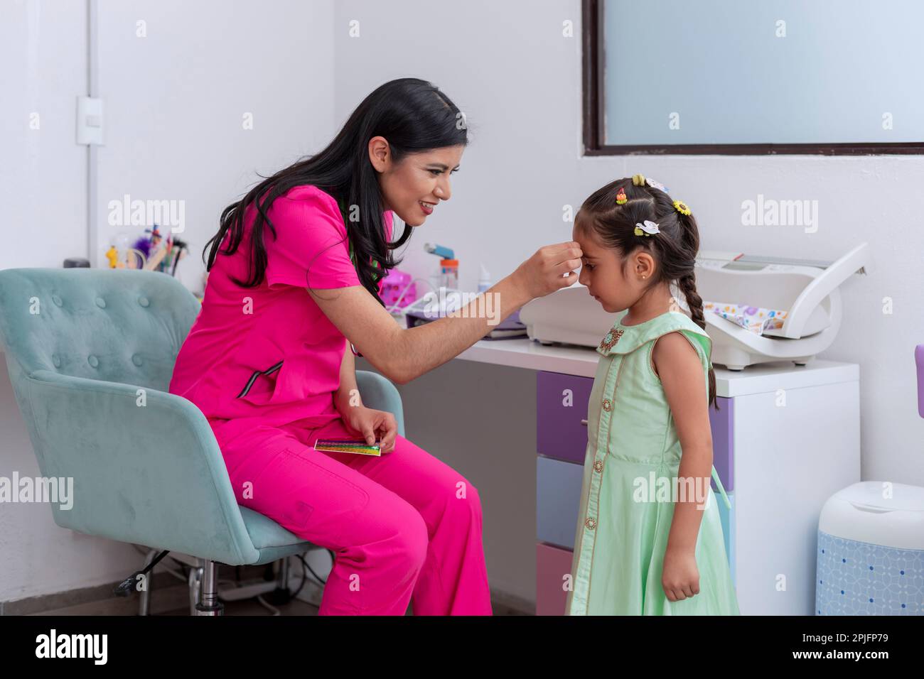 Pediatrician placing a star on the forehead of a girl, after her ...