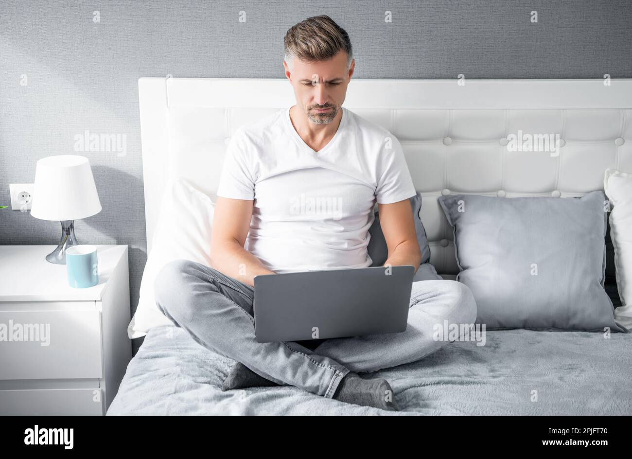 mature man using computer in bed with coffee Stock Photo - Alamy