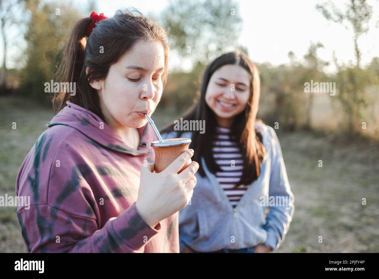 Two friends drinking yerba mate in the countryside at sunset. Copy ...