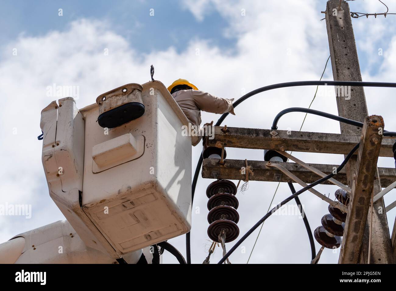 Male electrician standing in mobile crane basket and repairs a wire of ...