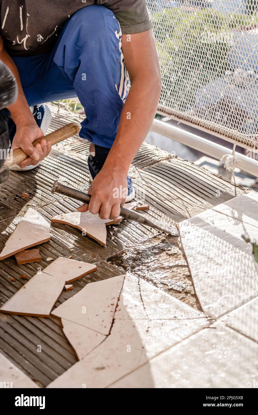Bricklayer breaking some floor tiles. Working in a construction ...